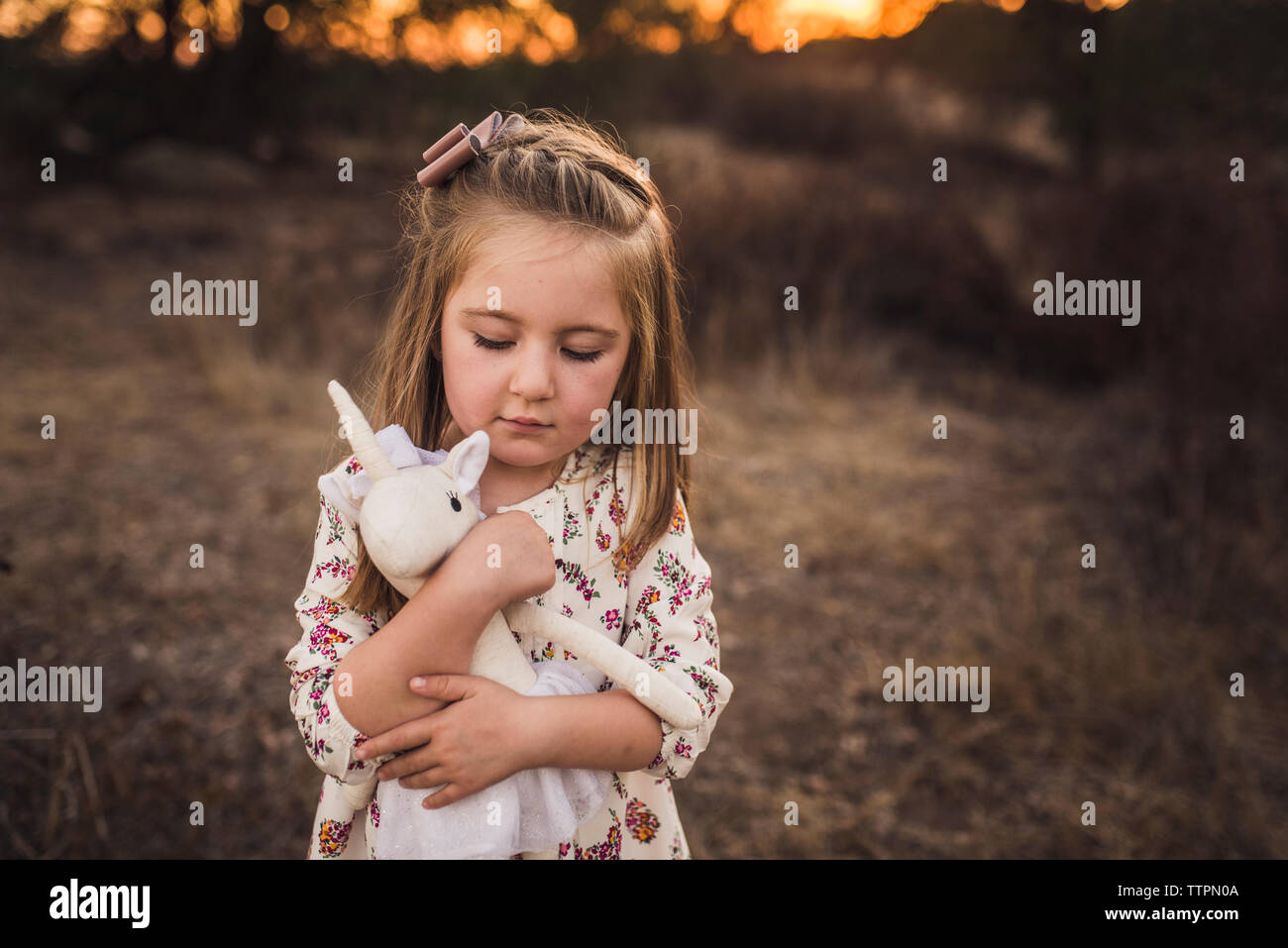 Portrait of young girl holding stuffed animal toy while looking down ...