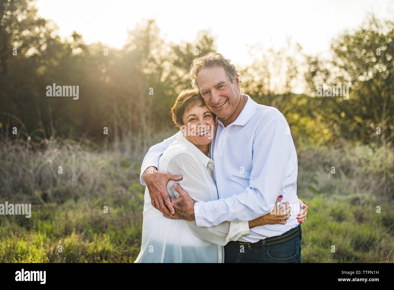 Senior couple hugging and smiling outside in backlight Stock Photo - Alamy