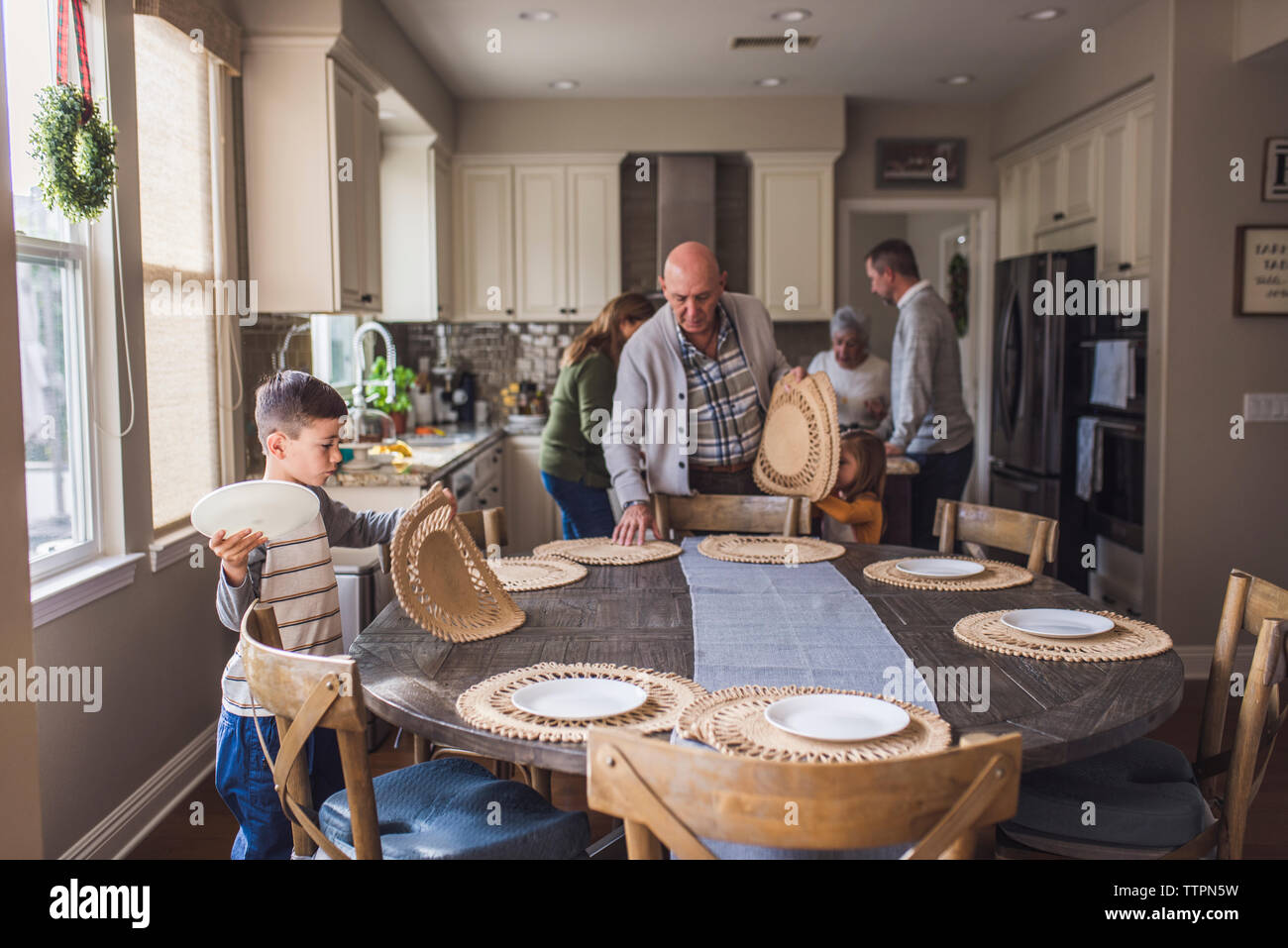 Family setting the kitchen table together for breakfast Stock Photo - Alamy