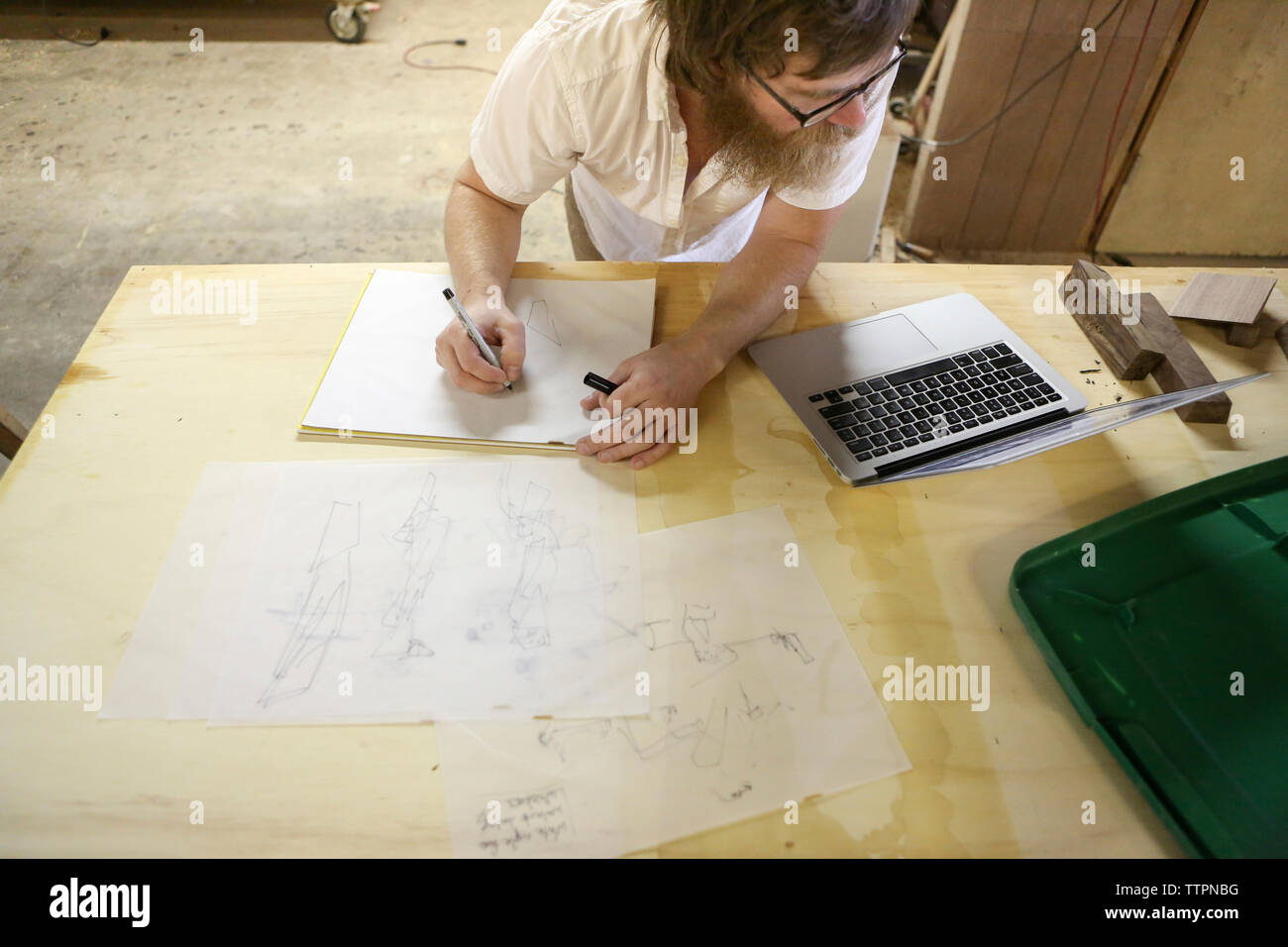 High angle view of carpenter with laptop computer drawing sketch on ...