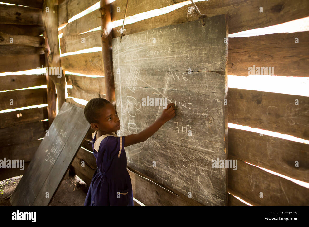 Side view of girl writing on blackboard in classroom Stock Photo - Alamy