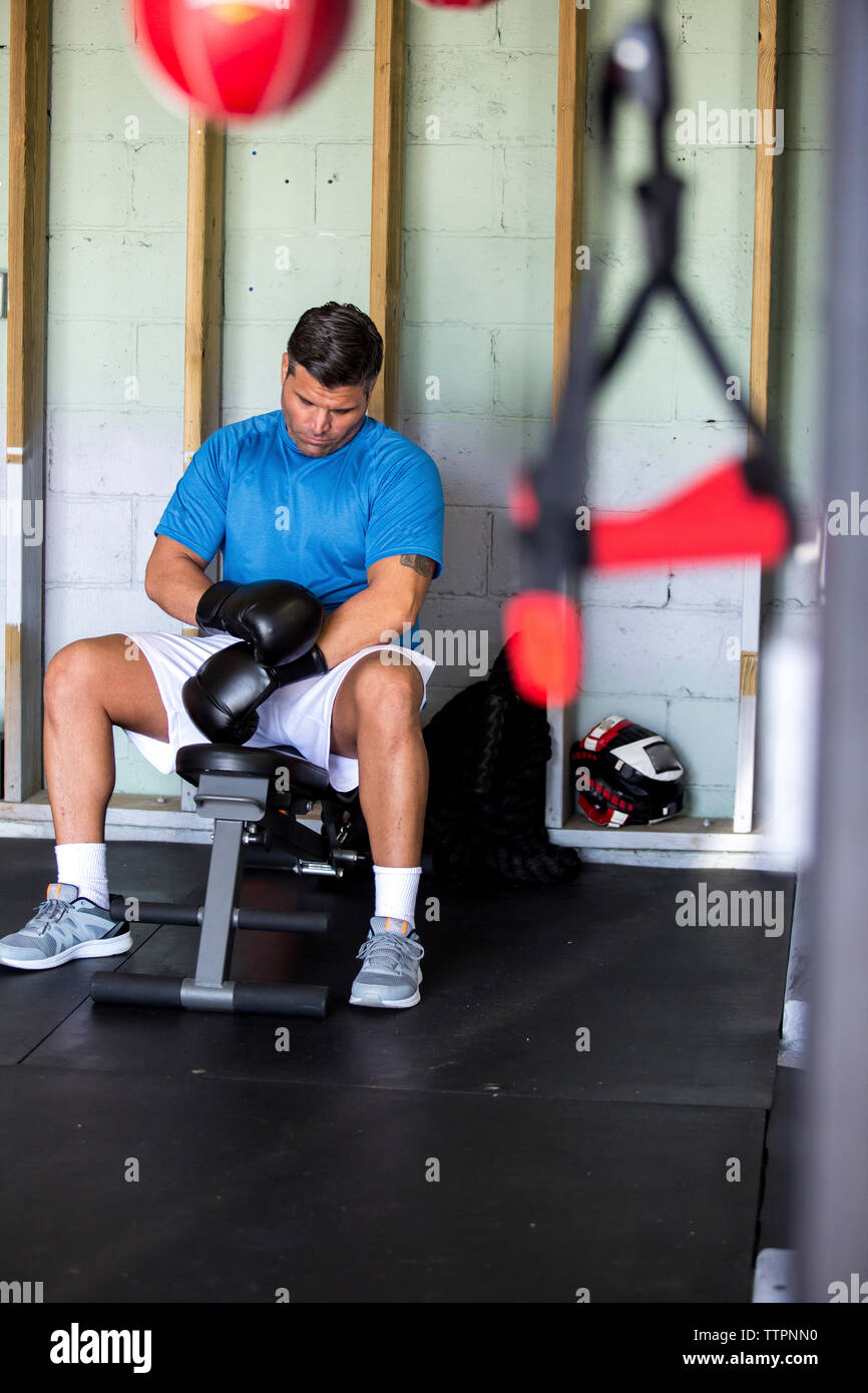 Boxer wearing boxing gloves while sitting in gym Stock Photo - Alamy