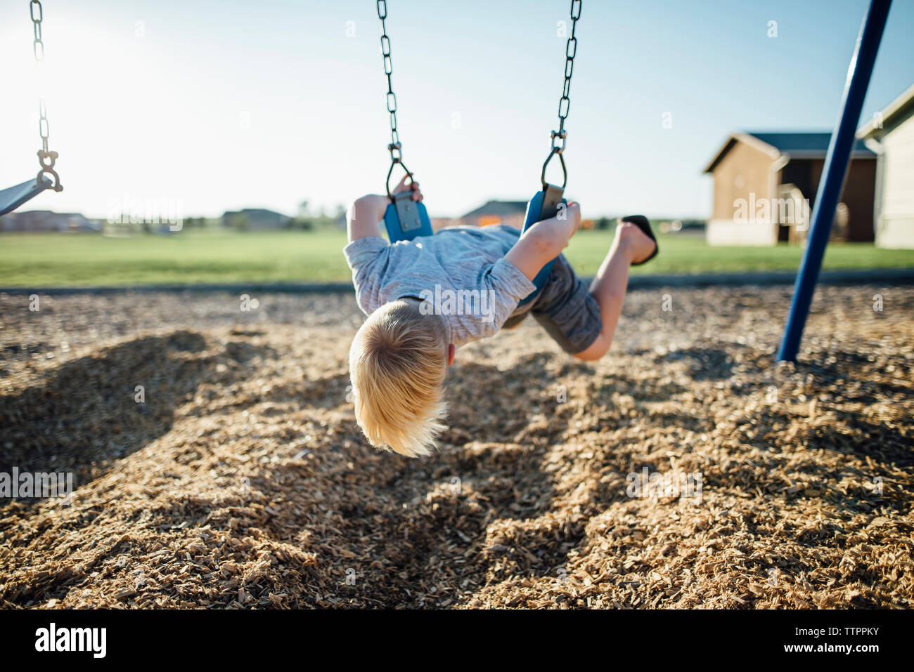 Boy playing on swing at park during sunny day Stock Photo - Alamy
