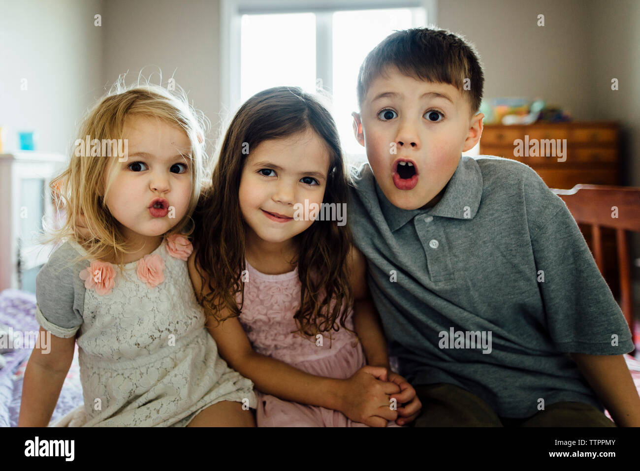 Portrait of siblings sitting on bed at home Stock Photo - Alamy