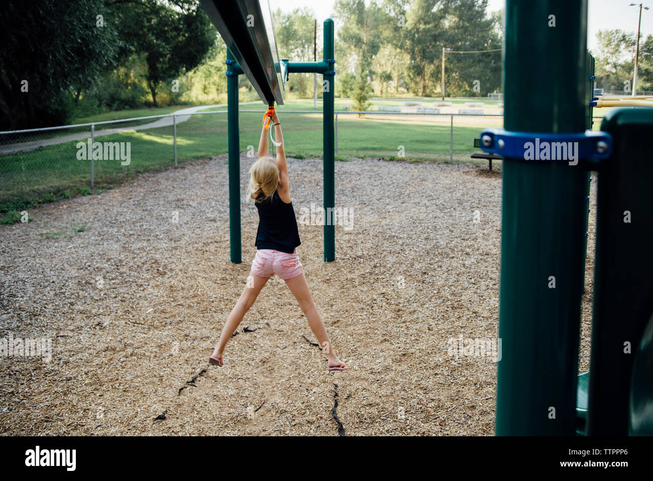 Rear view of girl zip lining at playground Stock Photo - Alamy