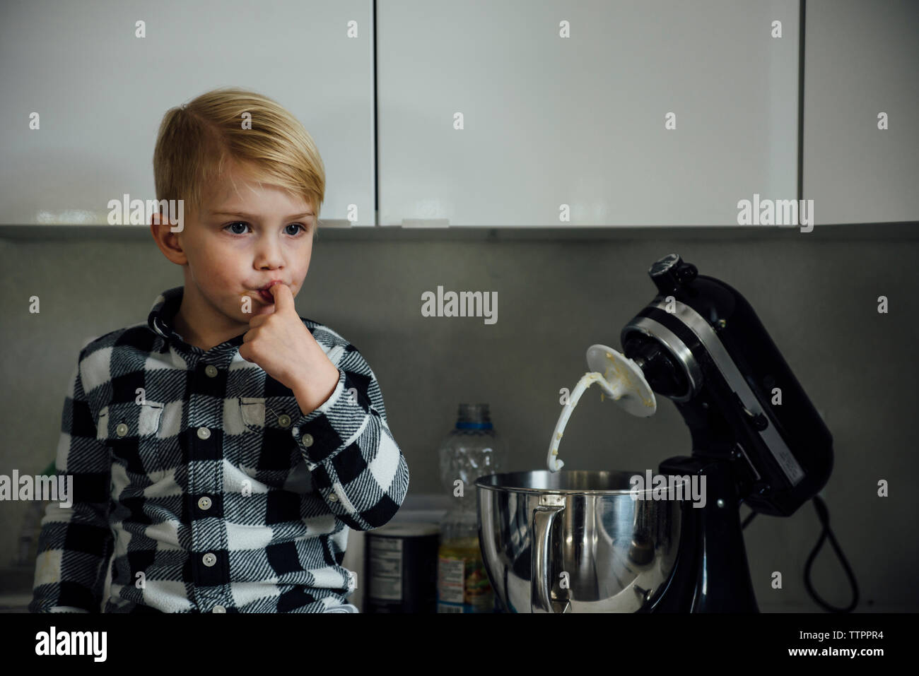 Cute boy tasting food from mixer in kitchen Stock Photo - Alamy