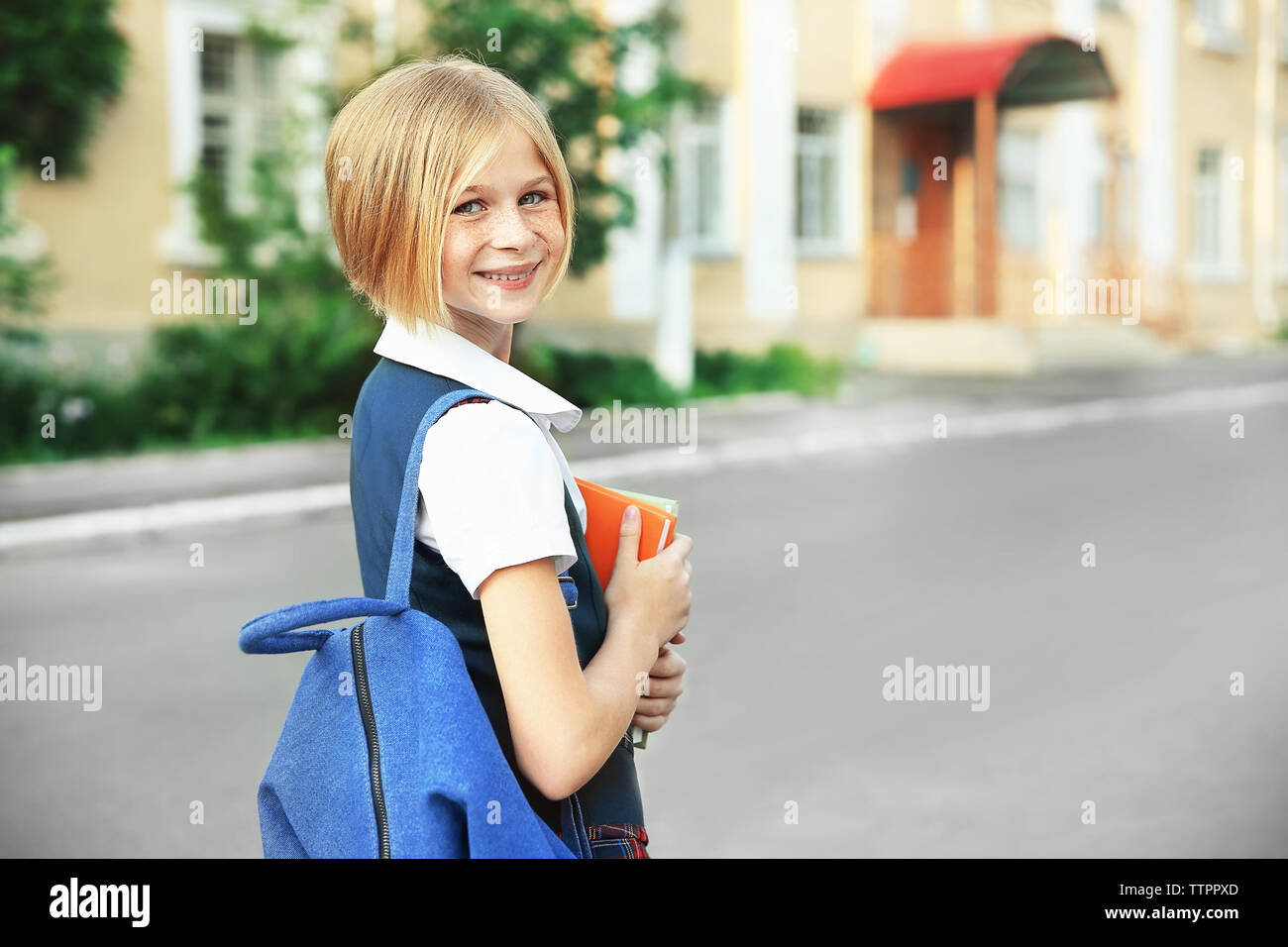 Cute schoolgirl with books on street Stock Photo - Alamy