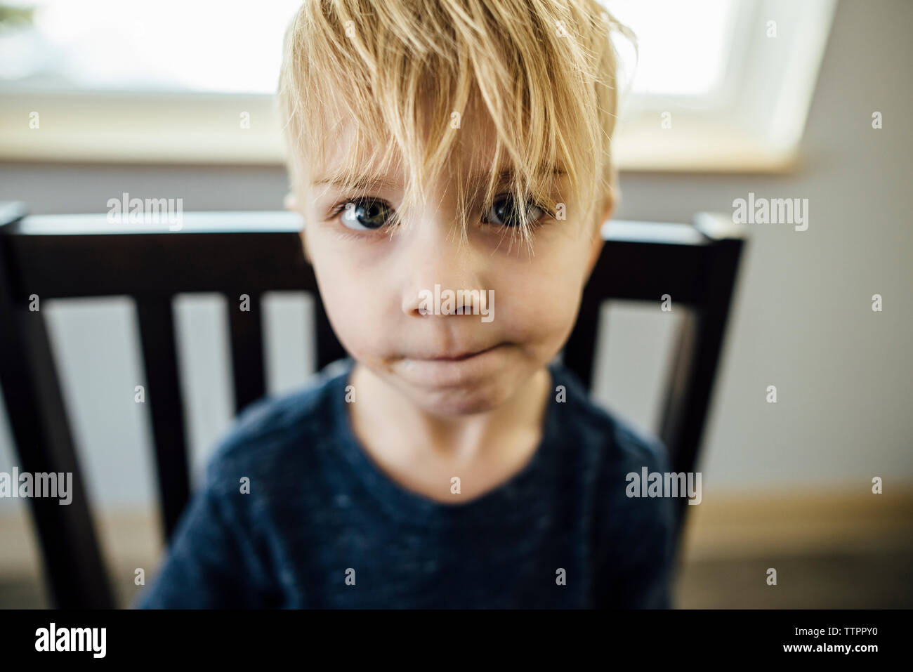 Close-up portrait of boy sitting on chair Stock Photo - Alamy