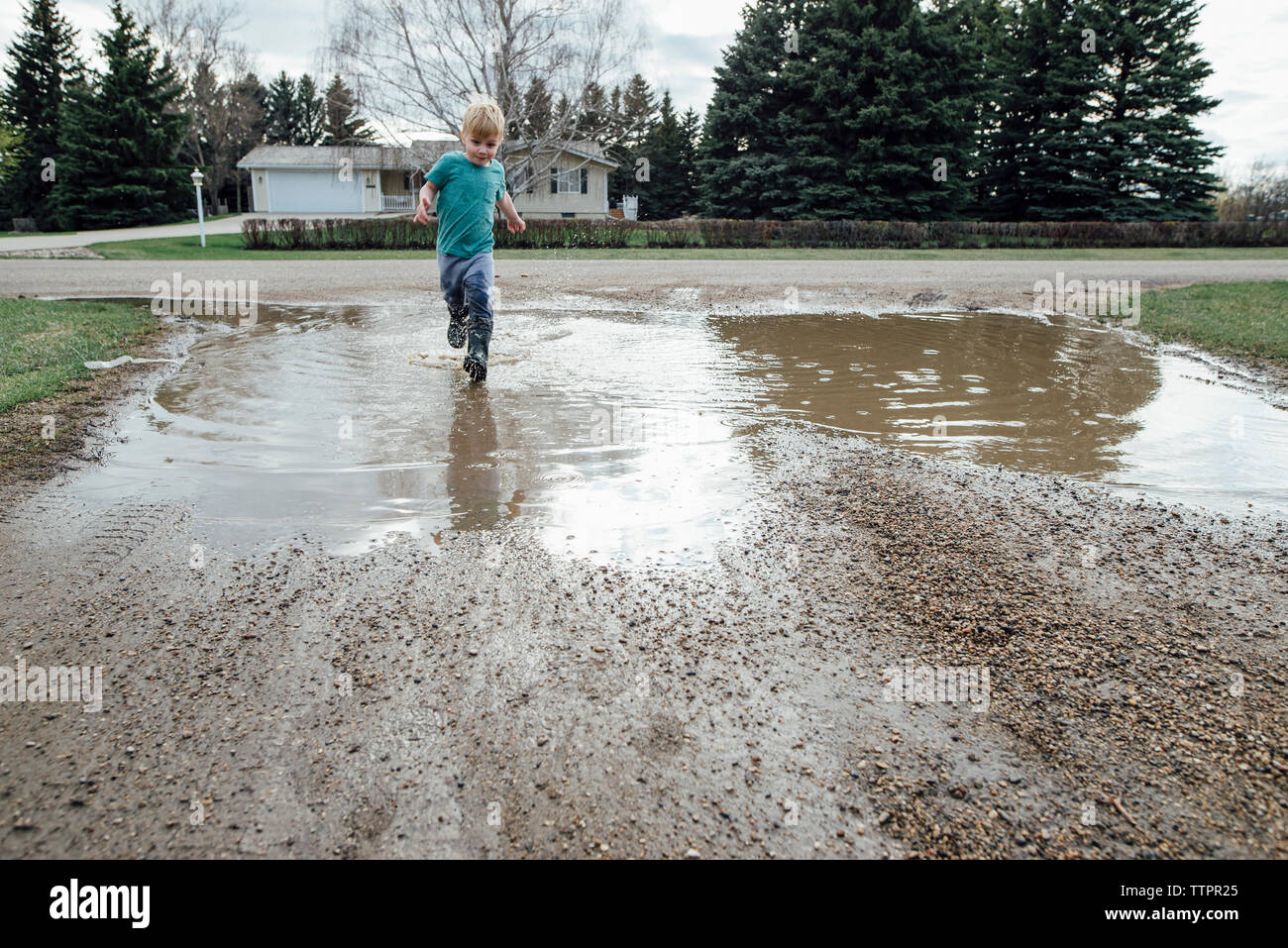 Playful boy running on puddle Stock Photo - Alamy