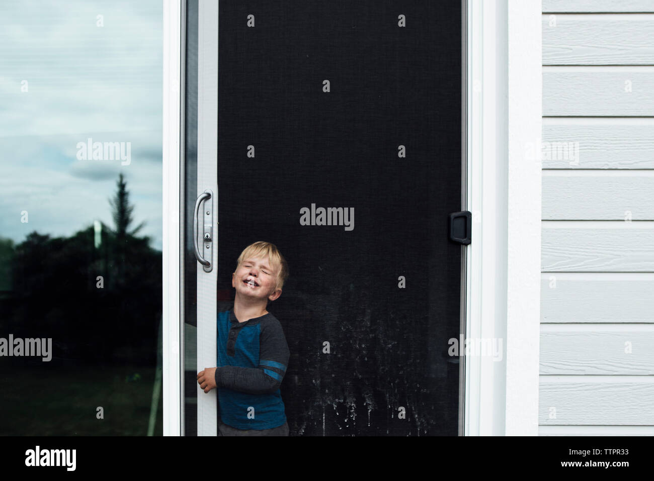 Boy crying while standing by window Stock Photo - Alamy