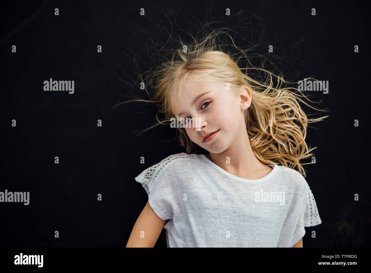 Portrait of girl standing against black background Stock Photo - Alamy