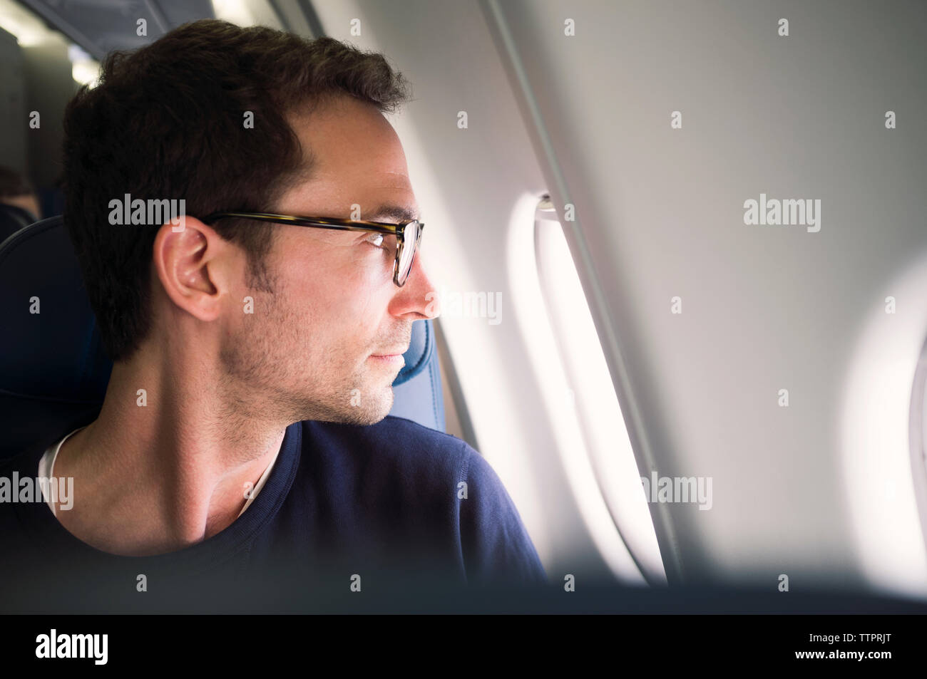 Close-up of man looking out through airplane window Stock Photo - Alamy