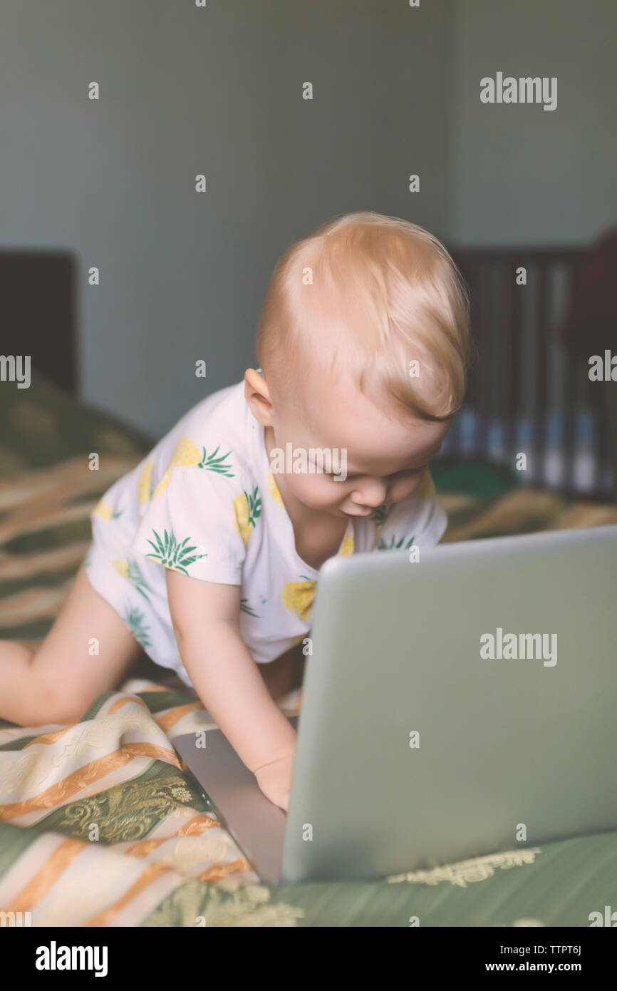 Cute baby boy using laptop computer on bed at home Stock Photo - Alamy