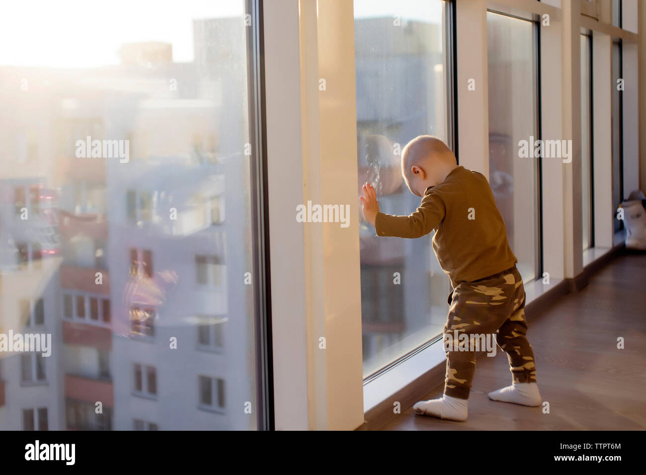 Full length of boy standing by window at home Stock Photo - Alamy