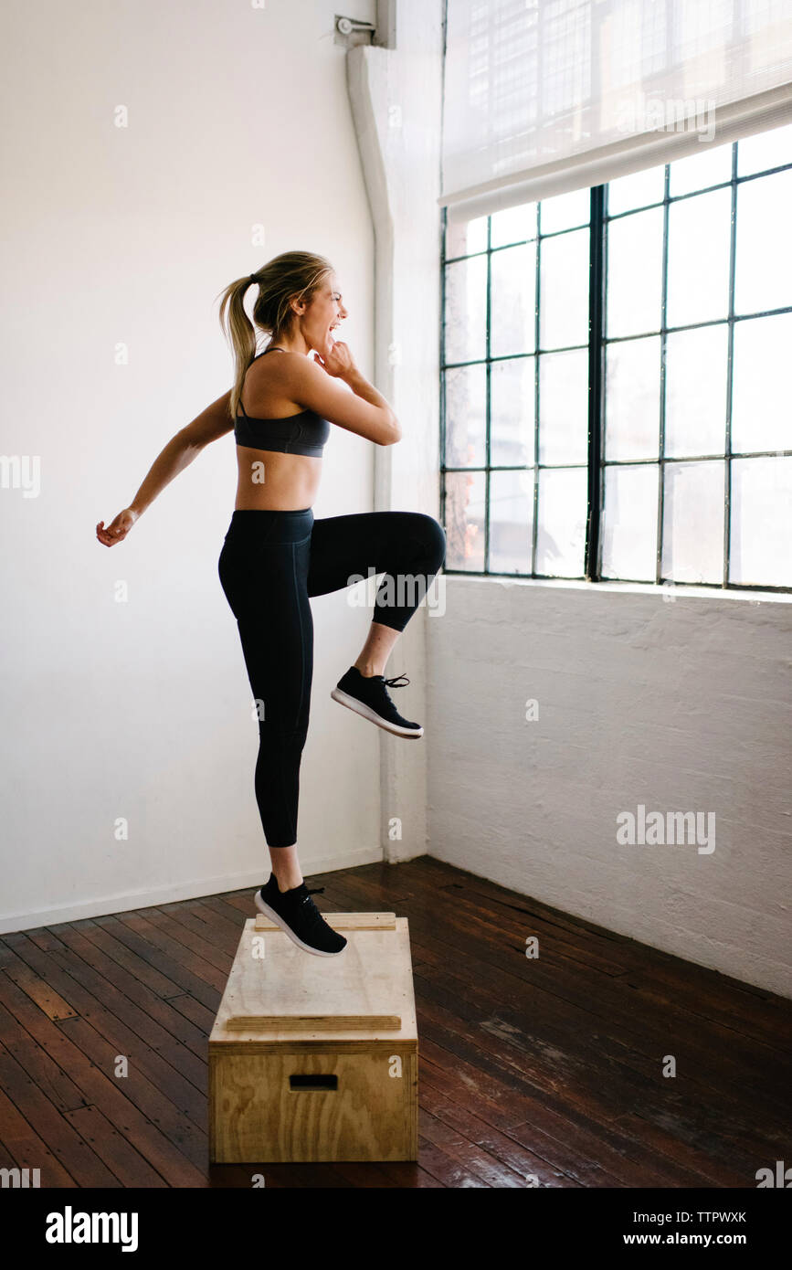 Athlete with mouth open jumping on wooden box in gym Stock Photo - Alamy