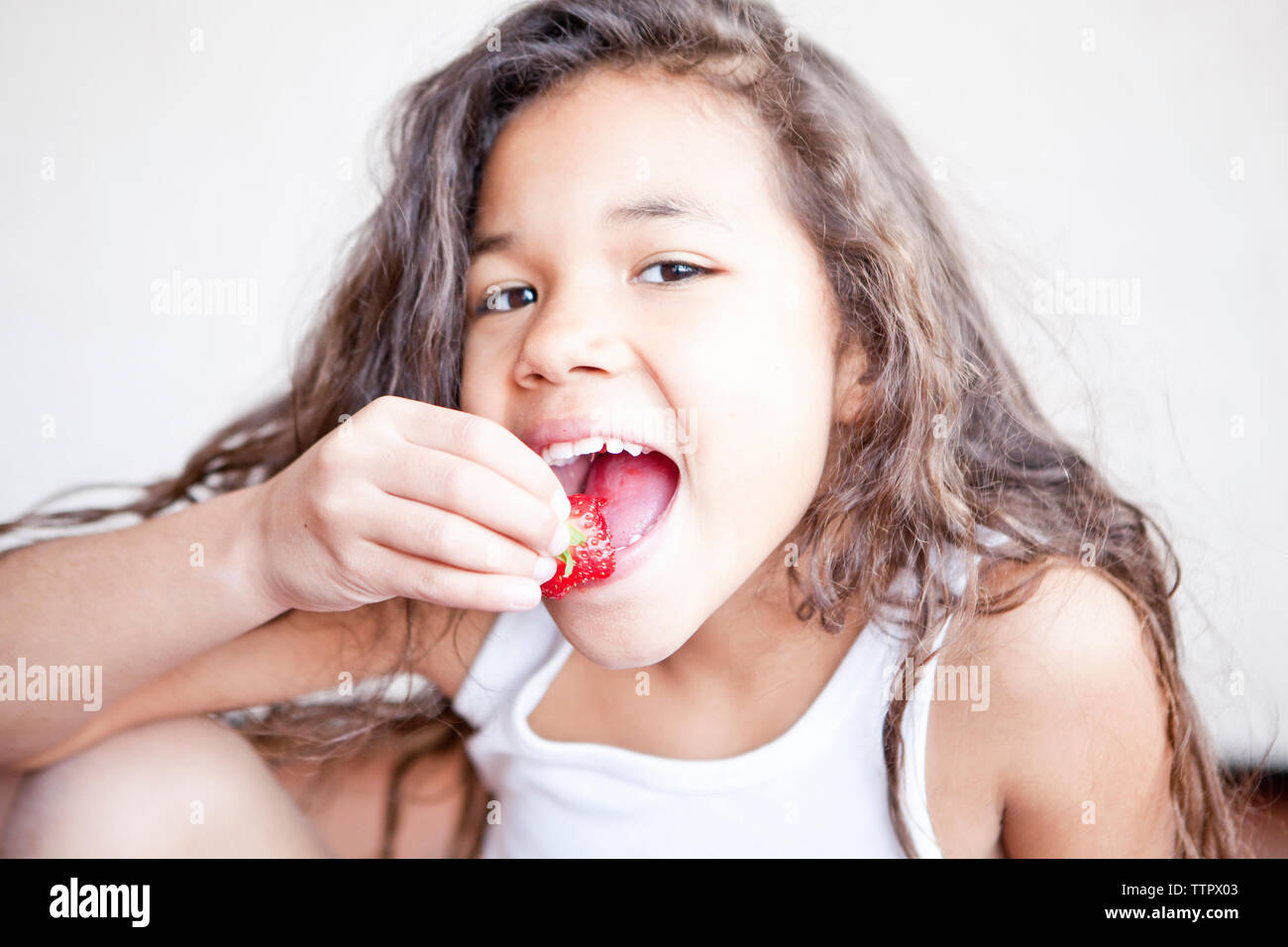 Portrait of happy girl eating strawberry at home Stock Photo - Alamy