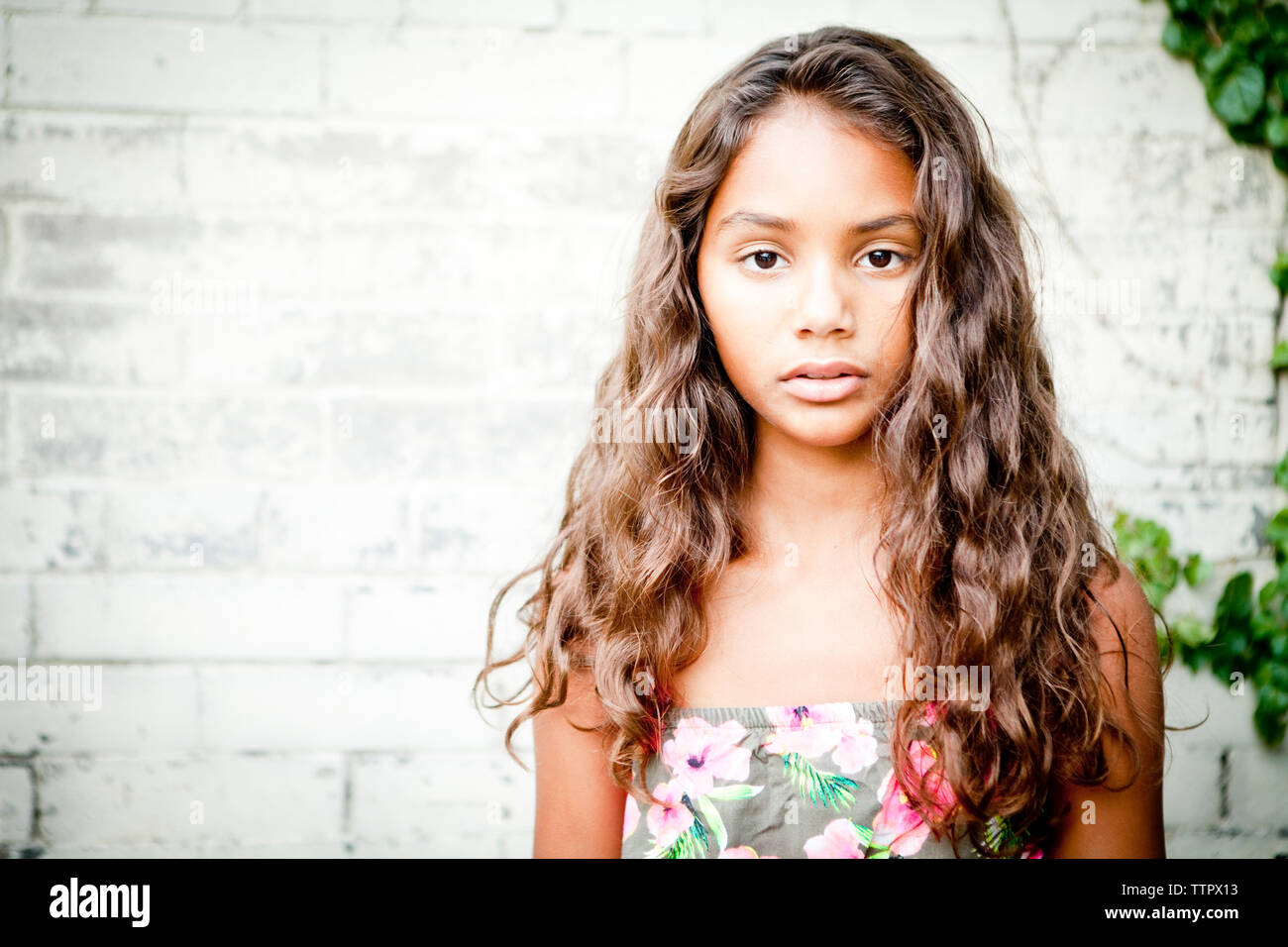 Portrait of serious girl standing against wall Stock Photo - Alamy