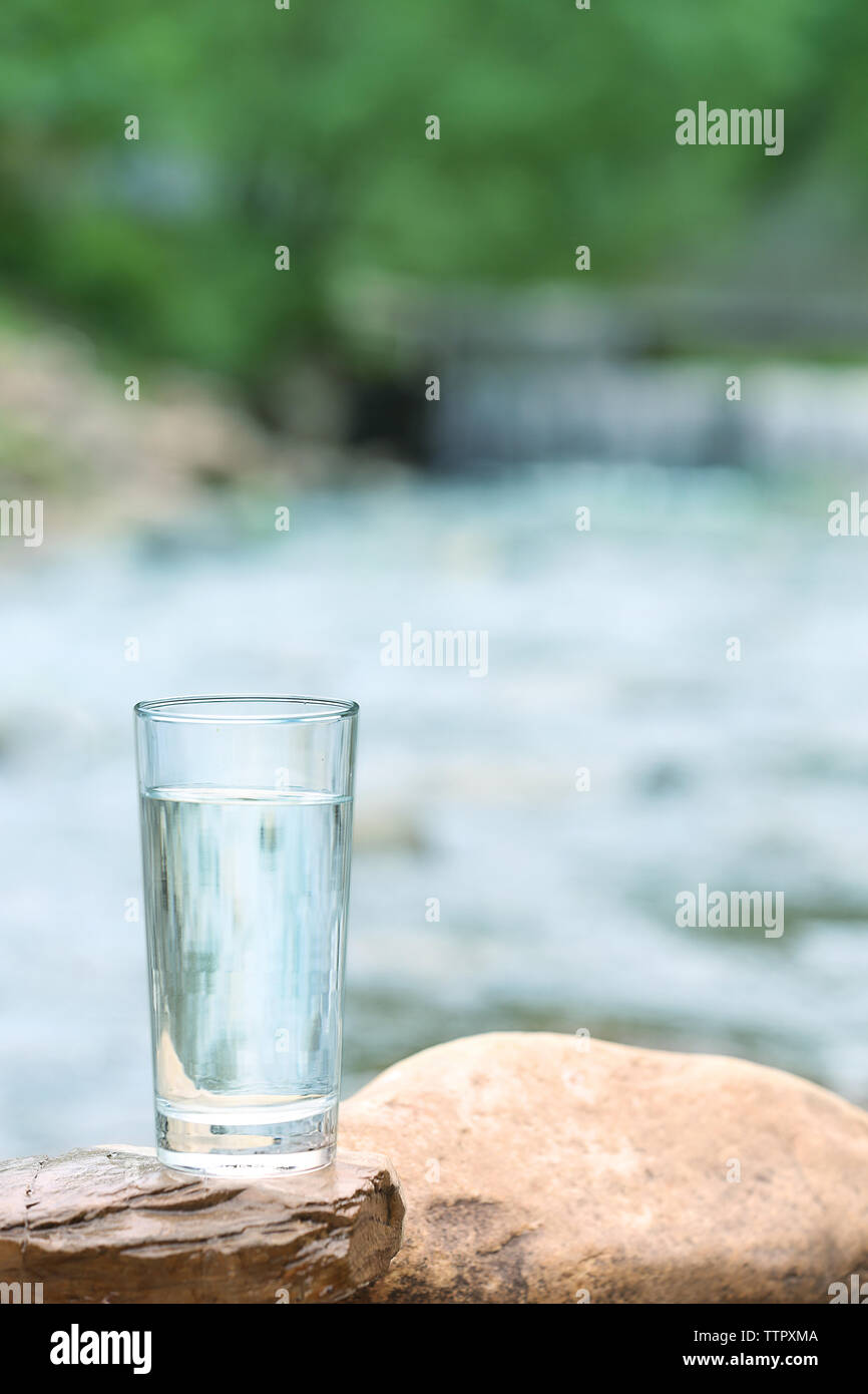Glass of water on blurred river background Stock Photo - Alamy