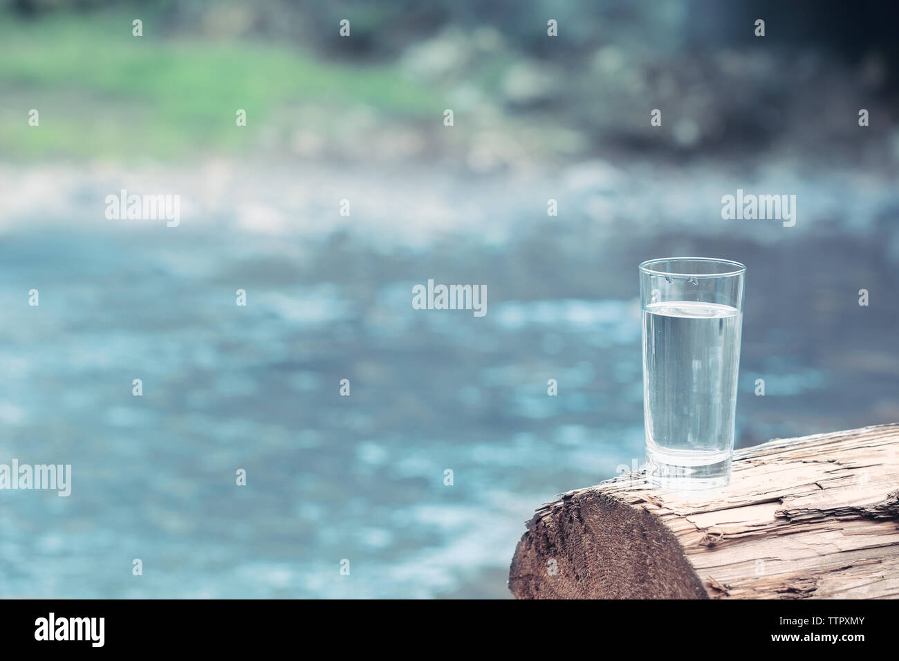 Glass of water on blurred river background Stock Photo - Alamy