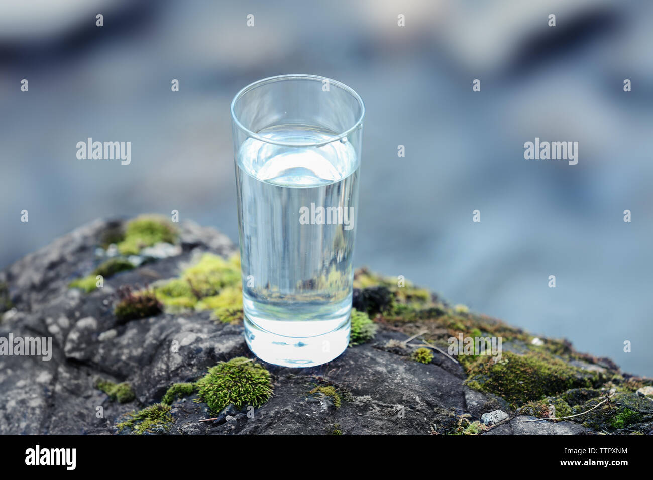 Glass of water on blurred river background Stock Photo - Alamy