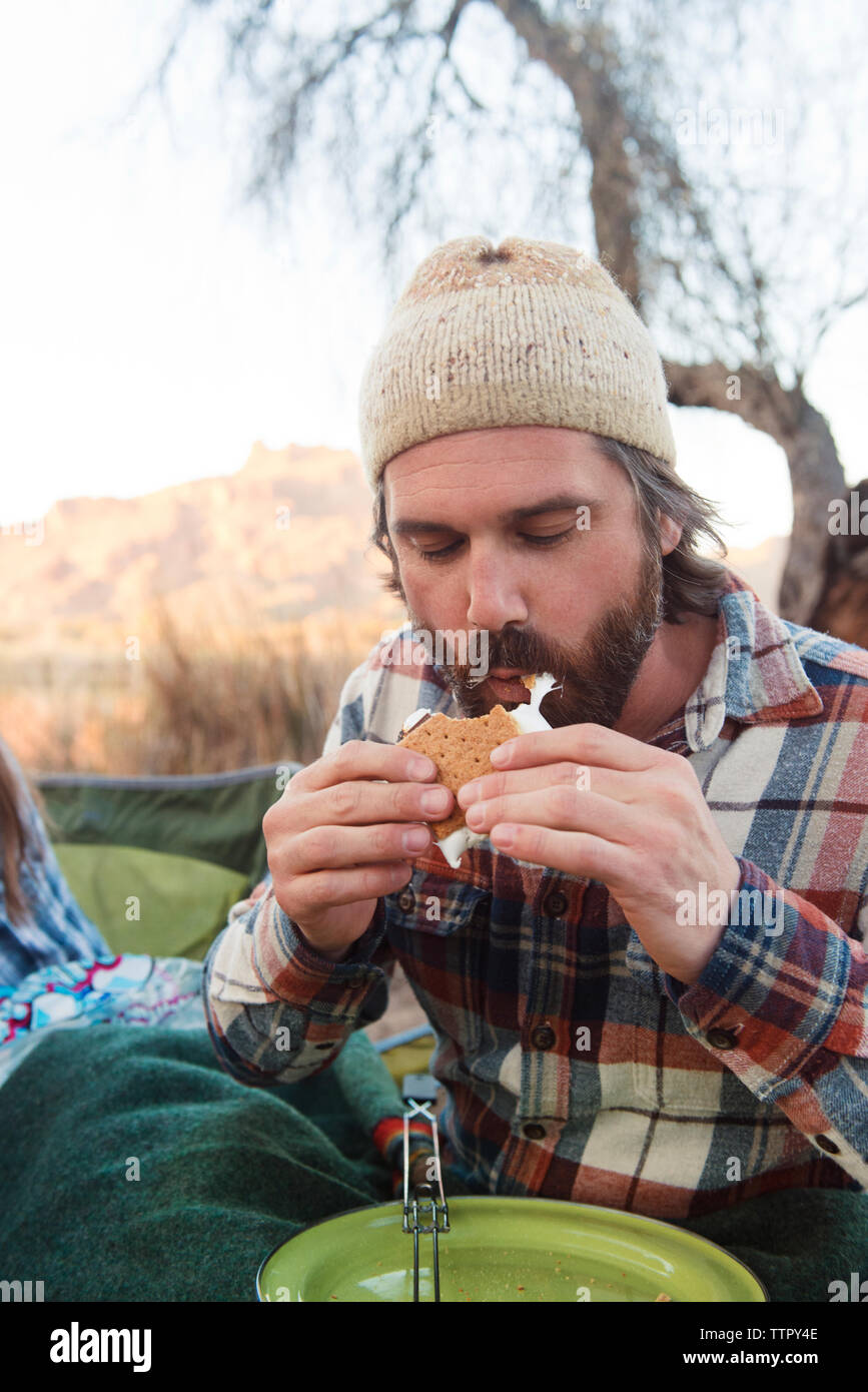 Mid adult man eating s'more at camp site Stock Photo - Alamy