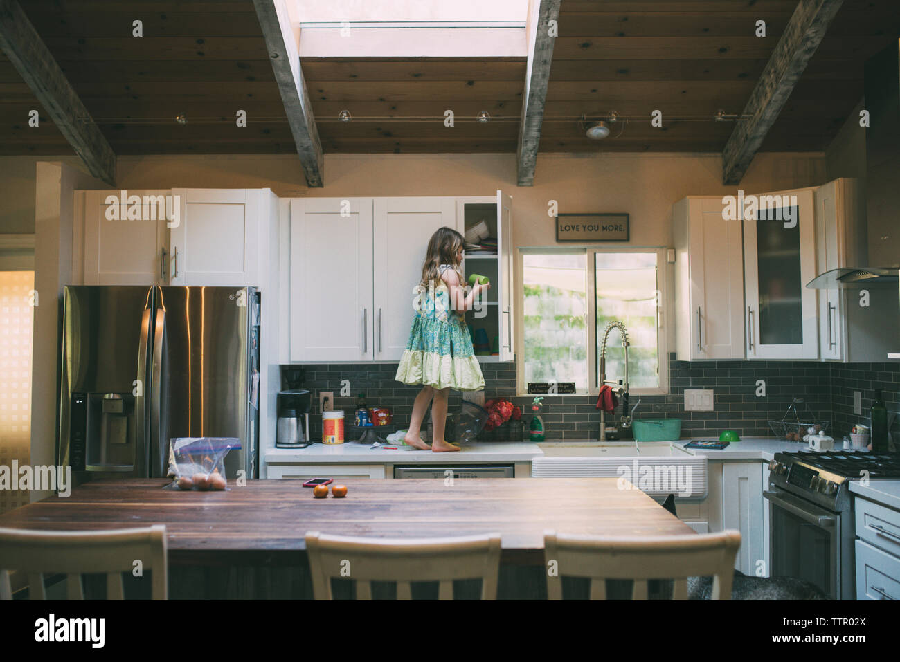 Side view of girl standing on kitchen counter Stock Photo - Alamy