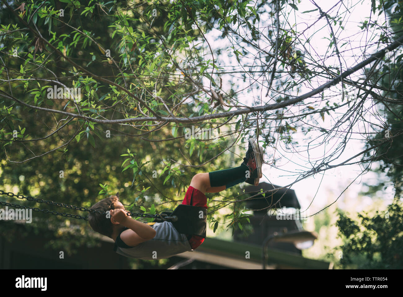 Carefree boy swinging at playground Stock Photo - Alamy