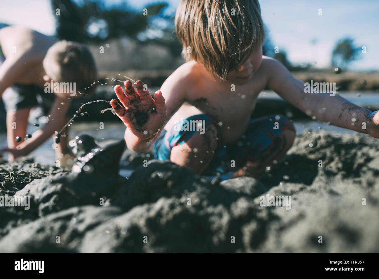 Brothers playing in mud at beach Stock Photo - Alamy