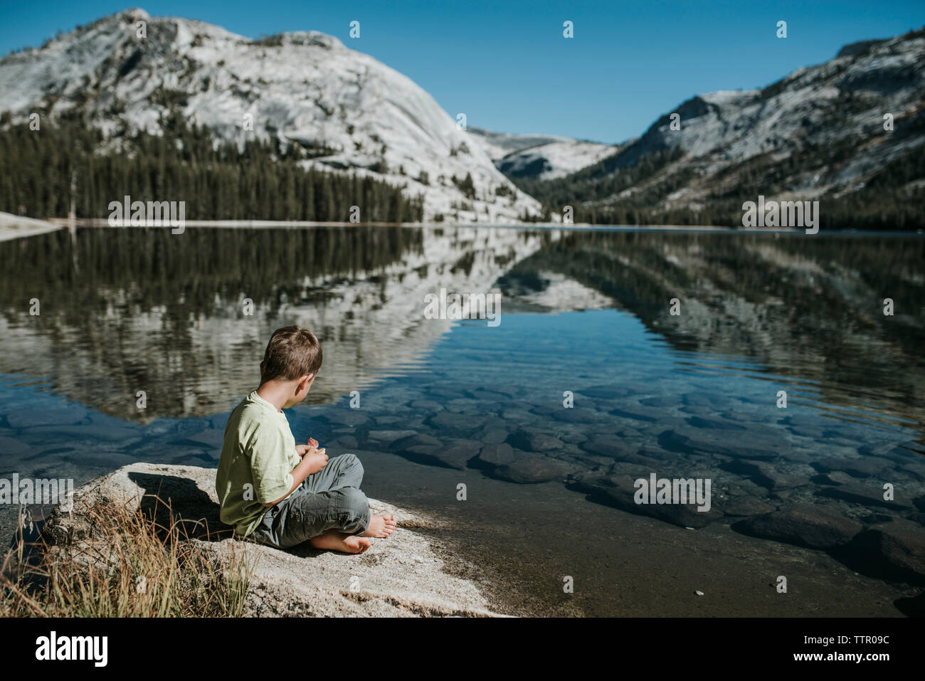Boy sitting on rocks by lake hi-res stock photography and images - Alamy