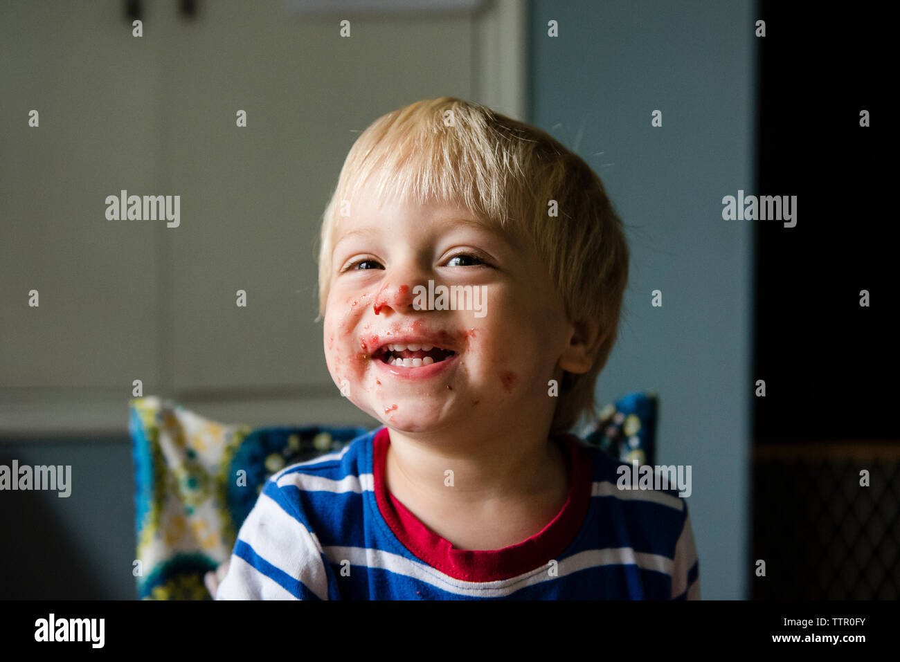 Cheerful boy with messy face sitting at home Stock Photo - Alamy