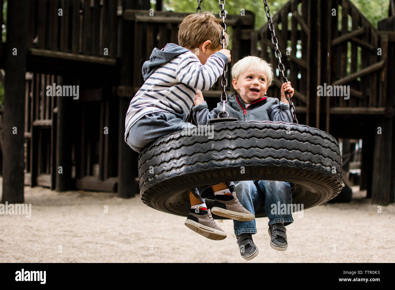 Happy brothers swinging in playground Stock Photo - Alamy