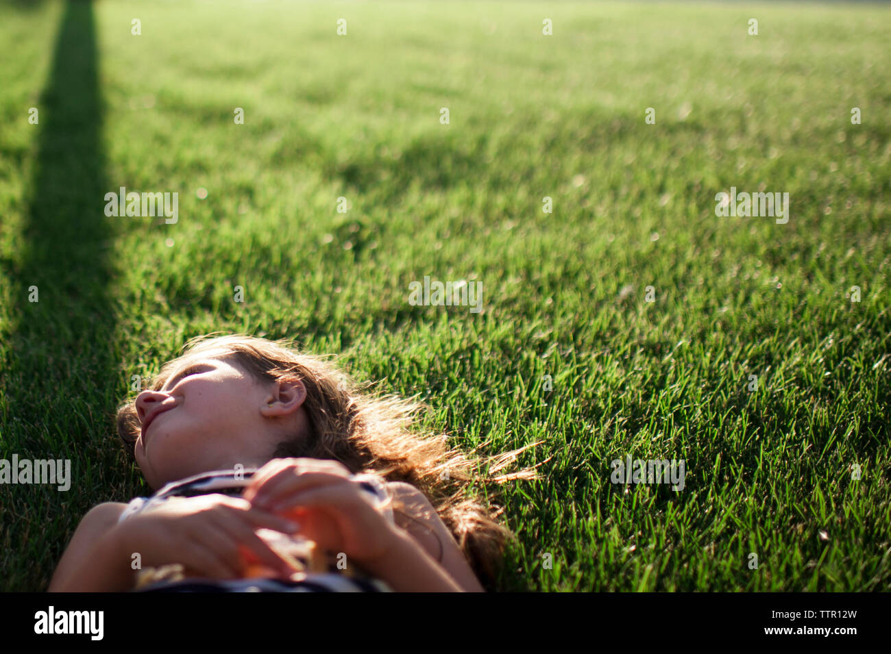 Smiling girl lying on grassy field Stock Photo - Alamy