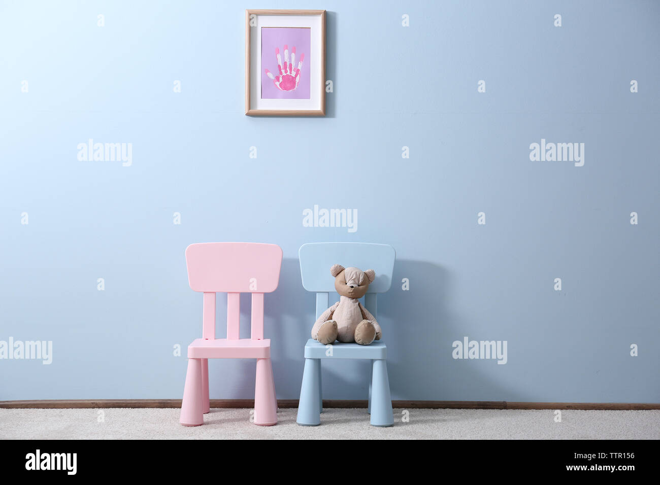 Two children chairs with toy on blue wall background Stock Photo - Alamy