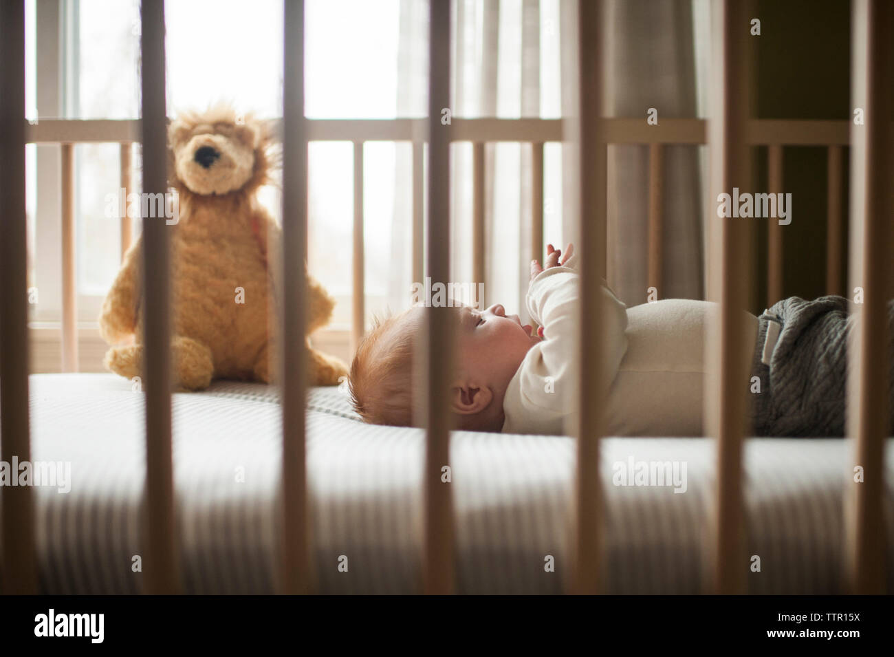 Side view of baby boy lying in crib Stock Photo - Alamy