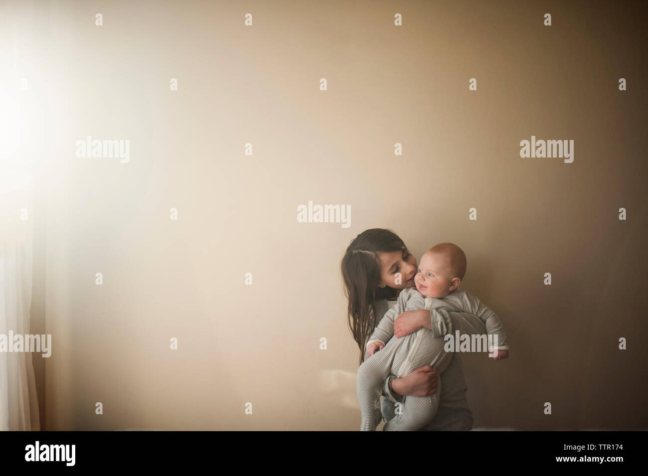 Sister carrying brother against wall at home Stock Photo - Alamy