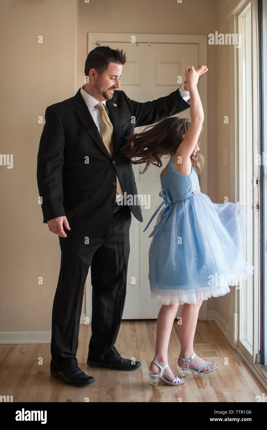 Daughter spinning while dancing with father on hardwood floor at home ...