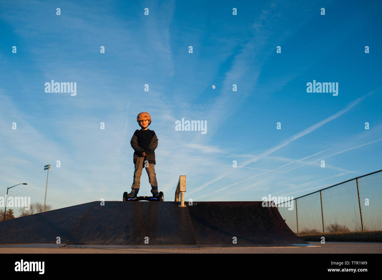 Young boy on top of pyramid ramp on his hover board at skate park Stock ...