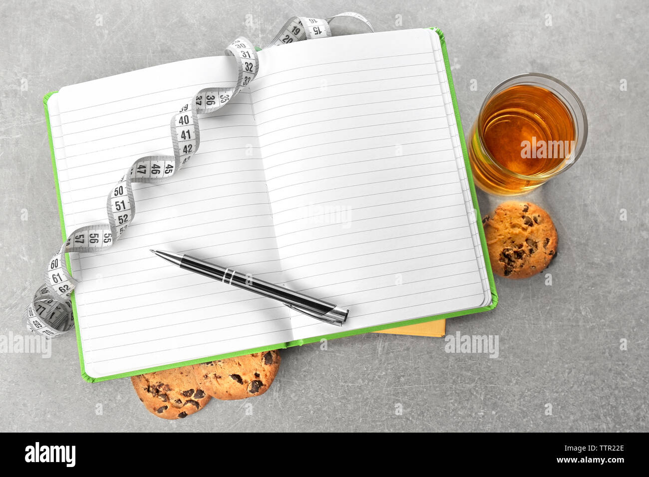 Notepad, measuring tape, juice and cookie on color background Stock ...