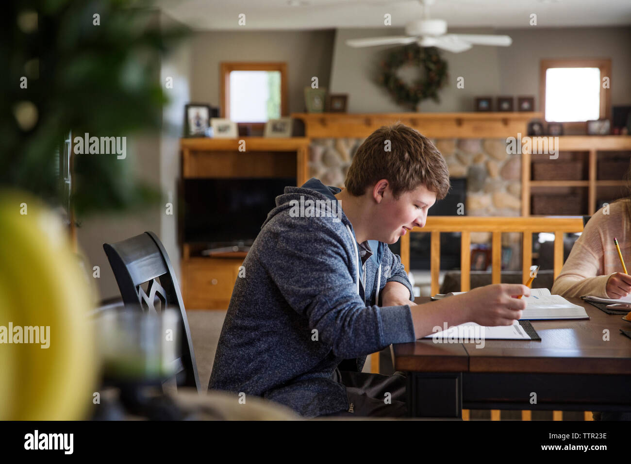 Side view of young man studying on table at home Stock Photo - Alamy