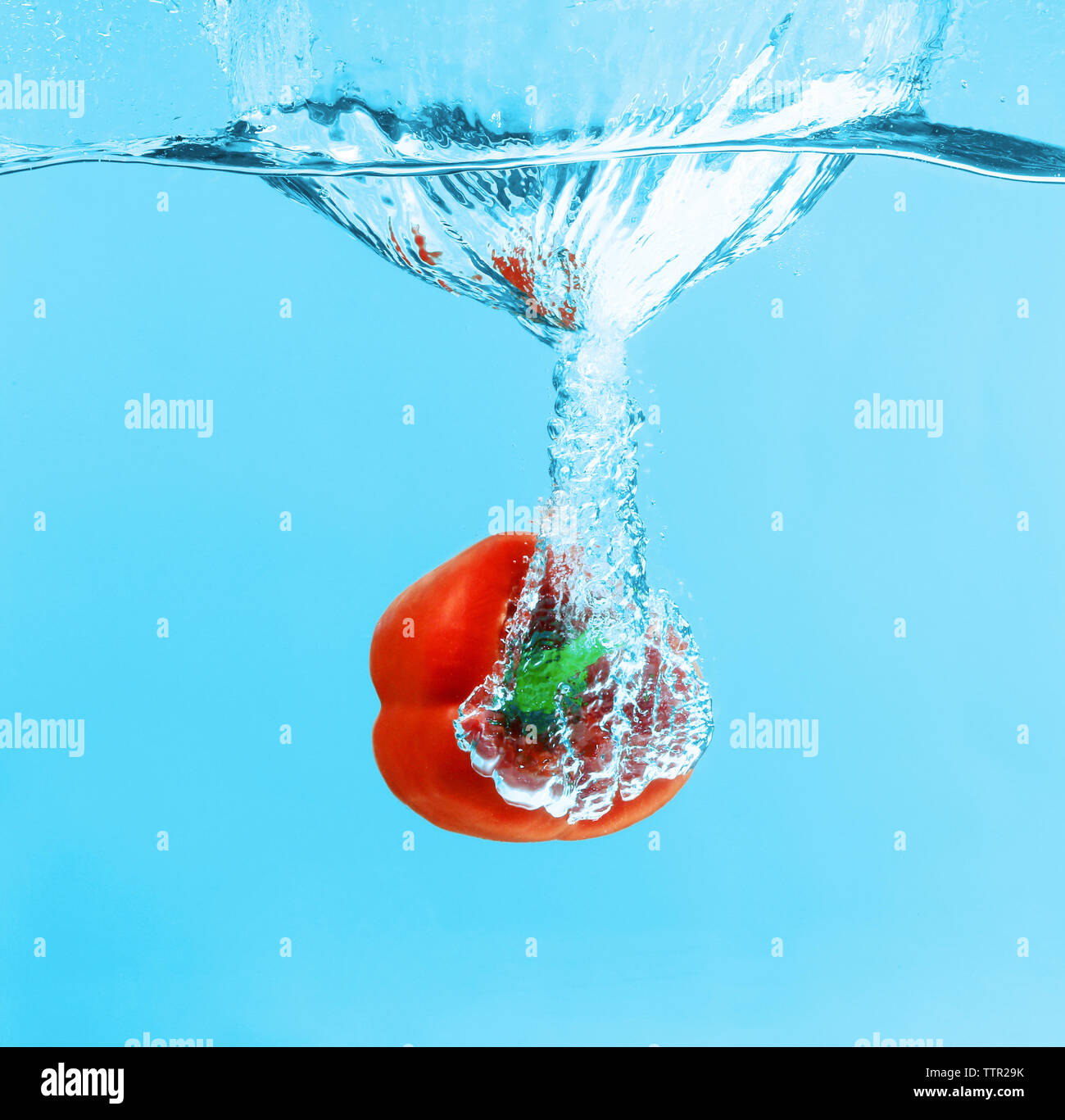 Pepper falling into water on color background Stock Photo - Alamy