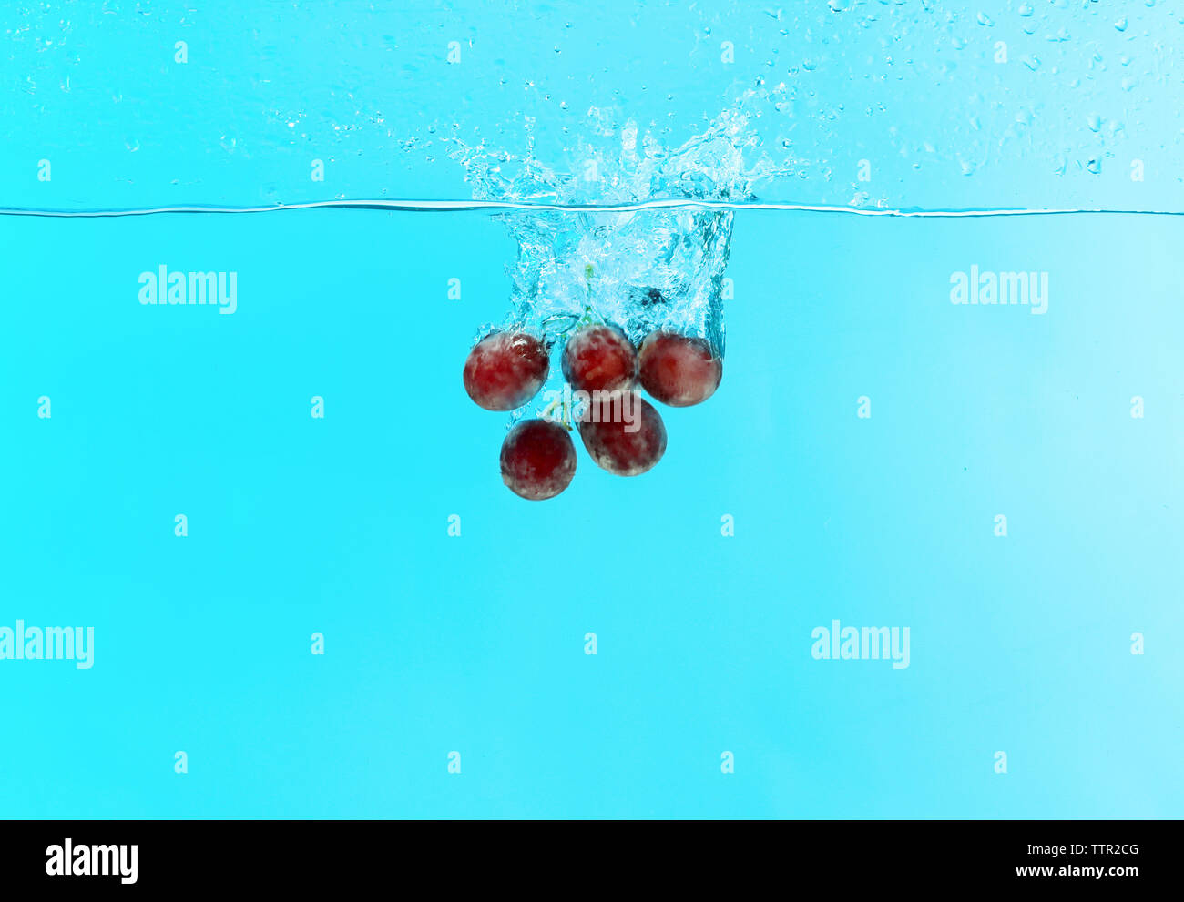 Grapes falling into water on color background Stock Photo - Alamy
