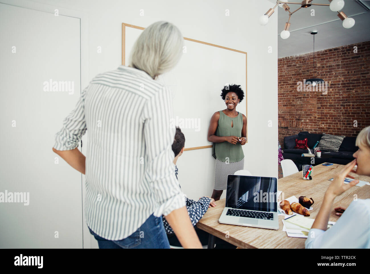 Happy businesswoman giving presentation to colleagues in board room ...