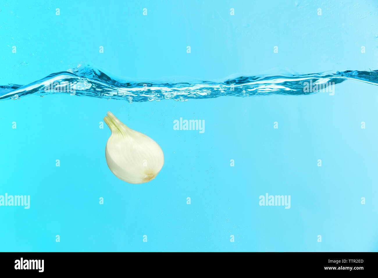 Onion falling into water on color background Stock Photo - Alamy