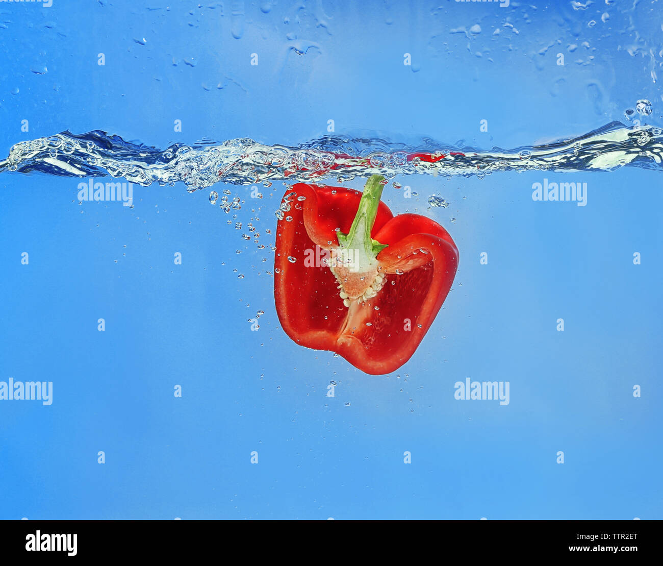 Pepper falling into water on color background Stock Photo - Alamy