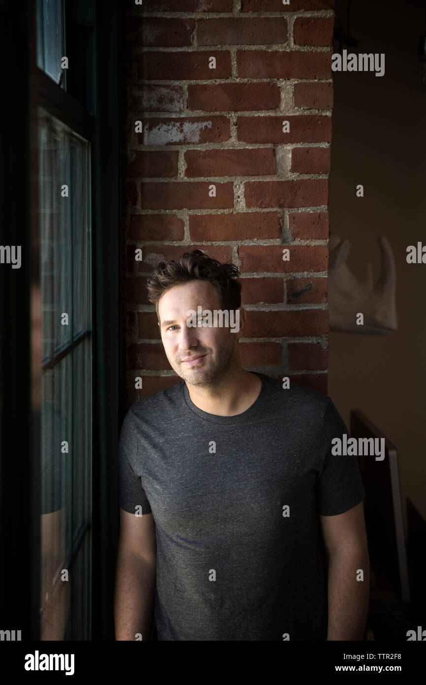 Portrait of man standing by window at home Stock Photo - Alamy