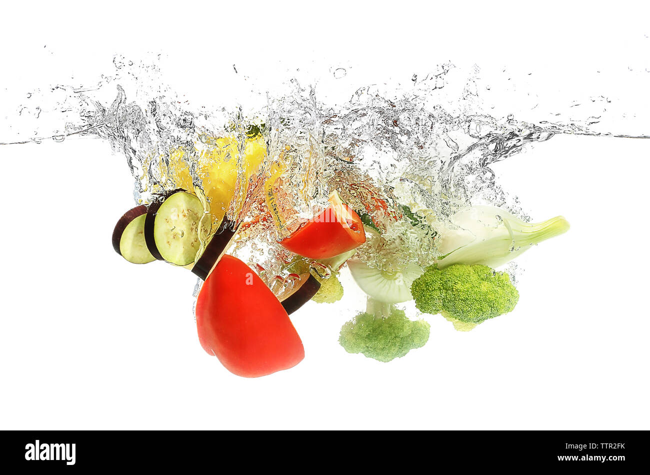 Vegetables falling into water on white background Stock Photo - Alamy