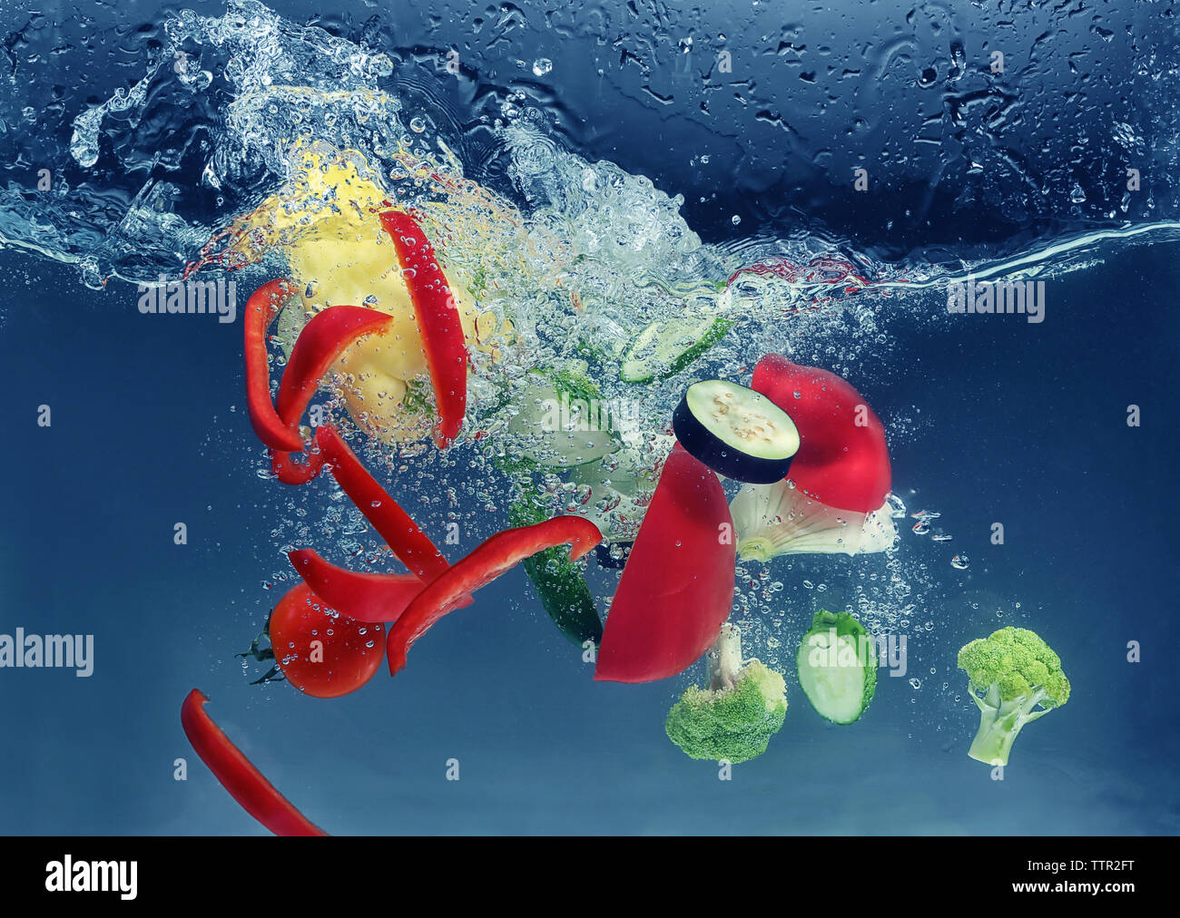 Vegetables falling into water on color background Stock Photo - Alamy
