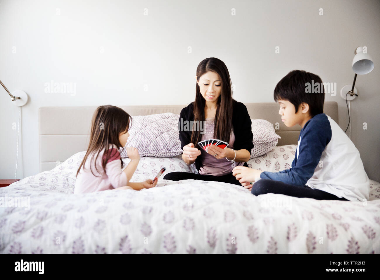 Family playing cards on bed at home Stock Photo - Alamy