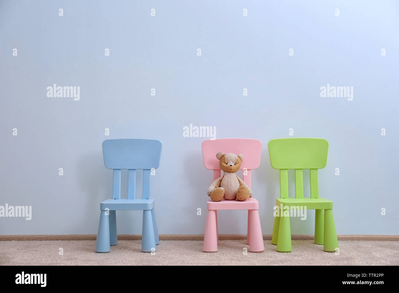 Three children chairs with toy on blue wall background Stock Photo - Alamy