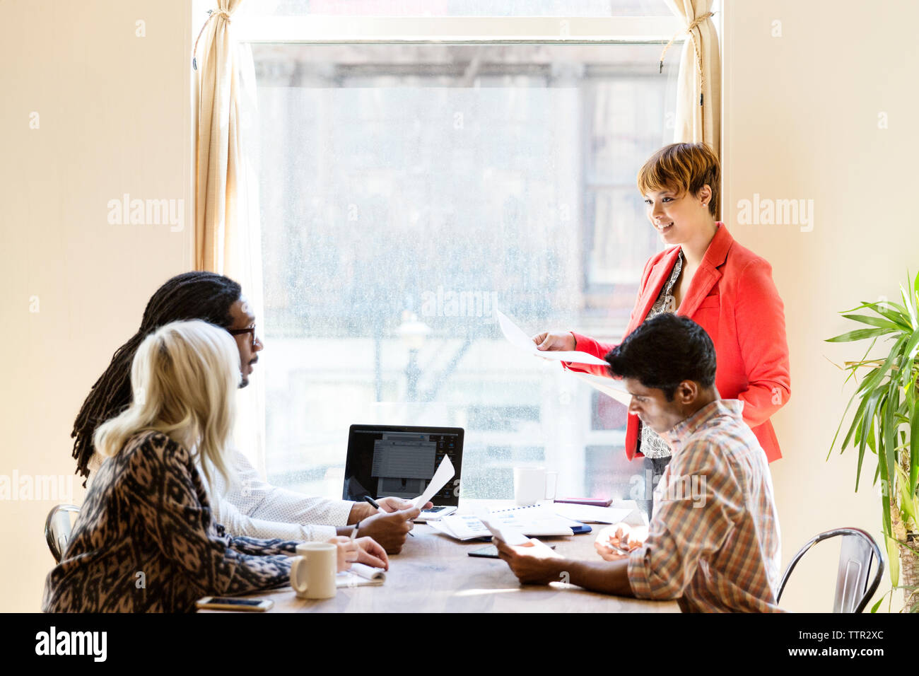 businesswoman giving presentation to colleagues during meeting at ...